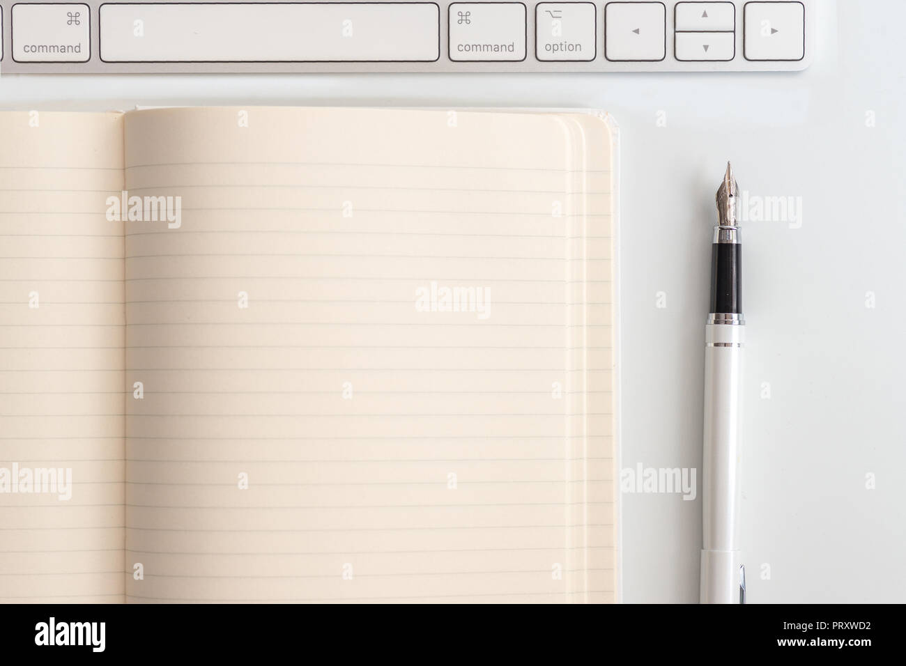 white table with notepad, keyboard and fountain pen. View from above ...