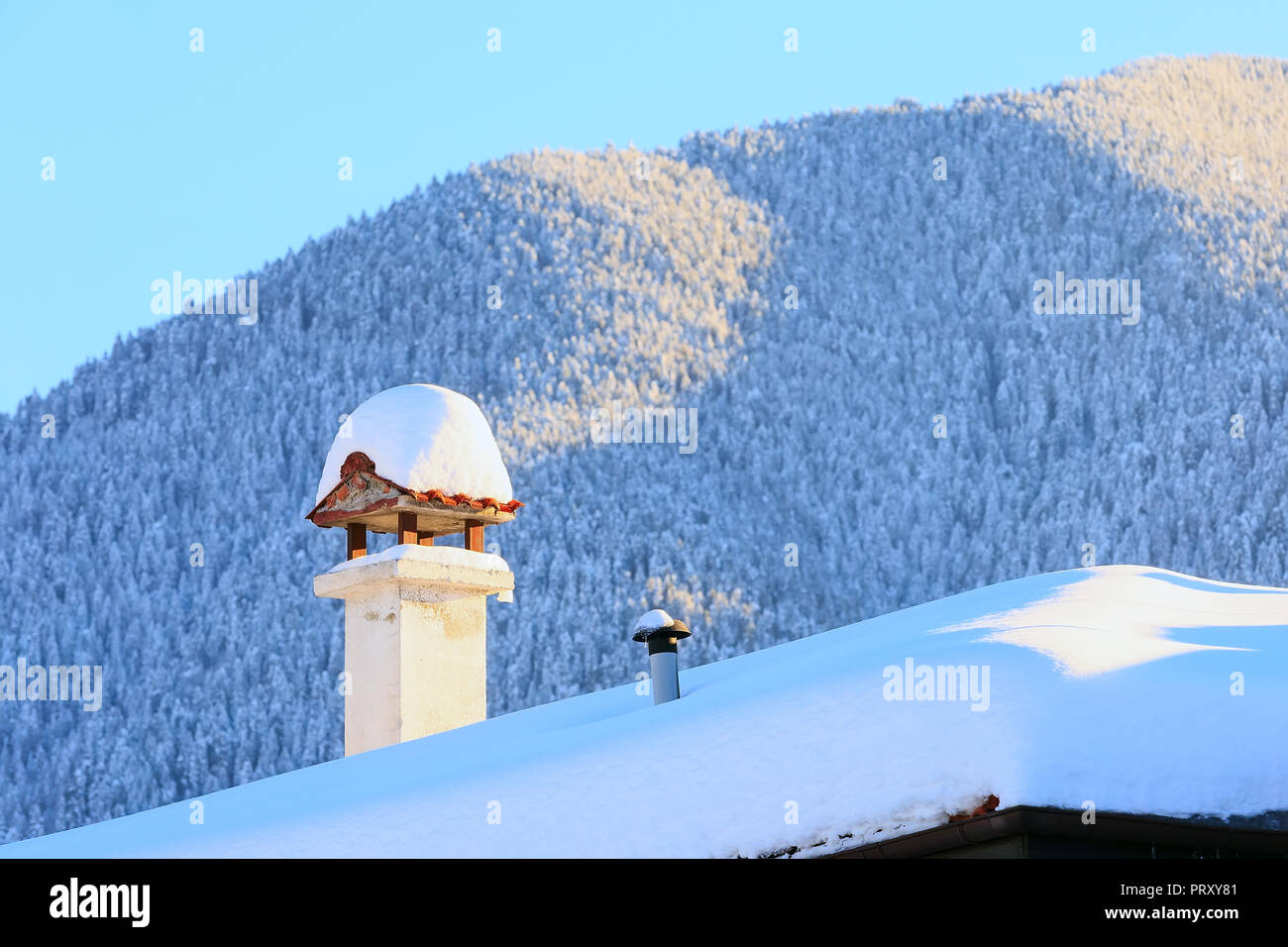 Snowy winter background. Chimney, house roof and mountain trees covered ...