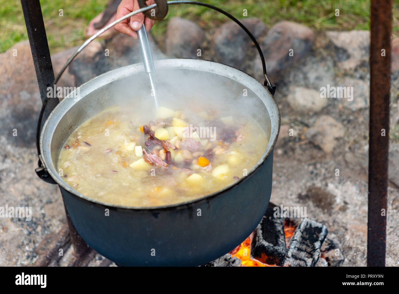 Cooking food in a pot on campfire. Summer camping concept Stock Photo ...