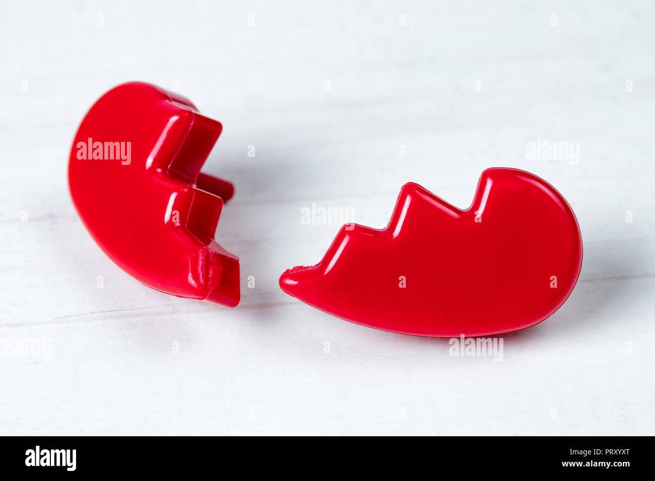 Two halves of broken red Valentines Day heart on white wooden ...