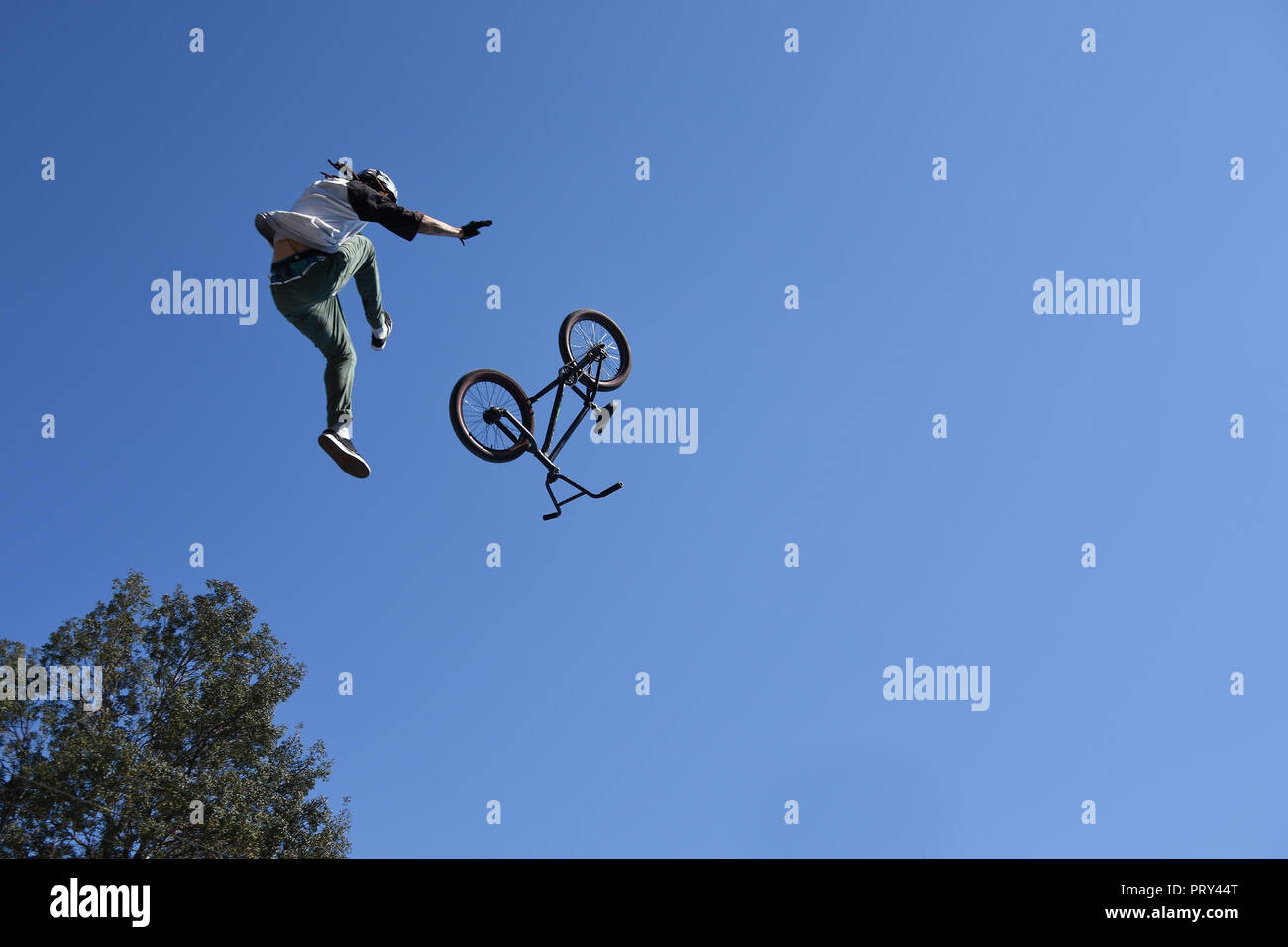 Young man freestyle stunt cyclist flying in the sky with his bike ...
