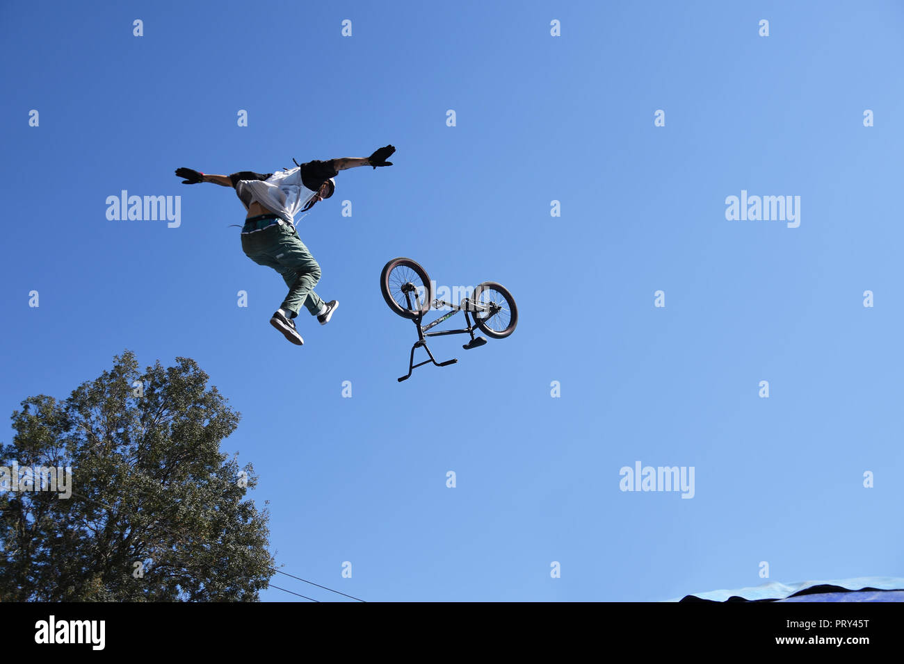 Young man freestyle stunt cyclist flying in the sky with his bike ...