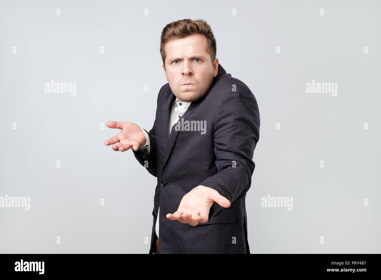 Confused angry young elegant man gestures in bewilderment, expresses ...