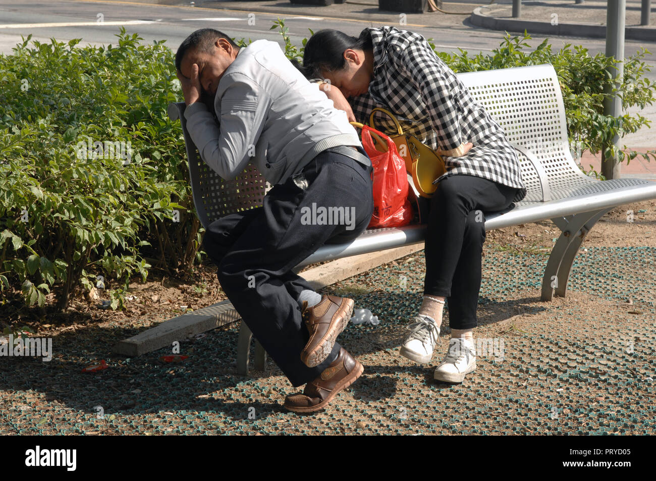 Couple sleeping on park bench, Macau Stock Photo - Alamy