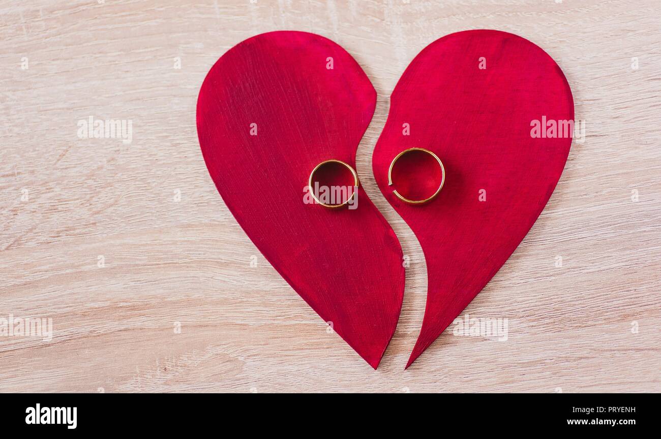 Two broken golden wedding rings on broken red heart. Divorce concept ...