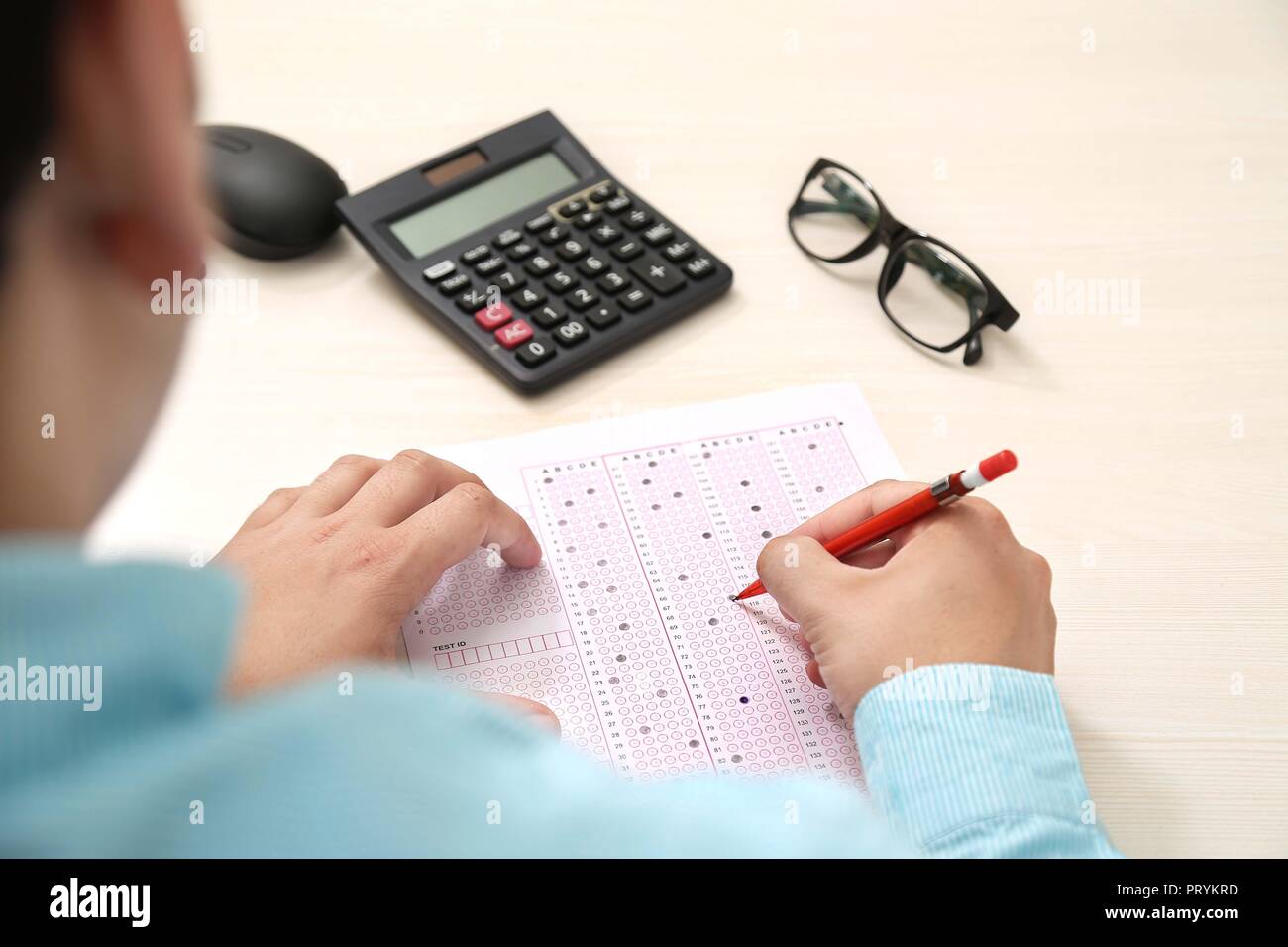Man is filling OMR sheet with pen. Picture of calculator, glasses and ...