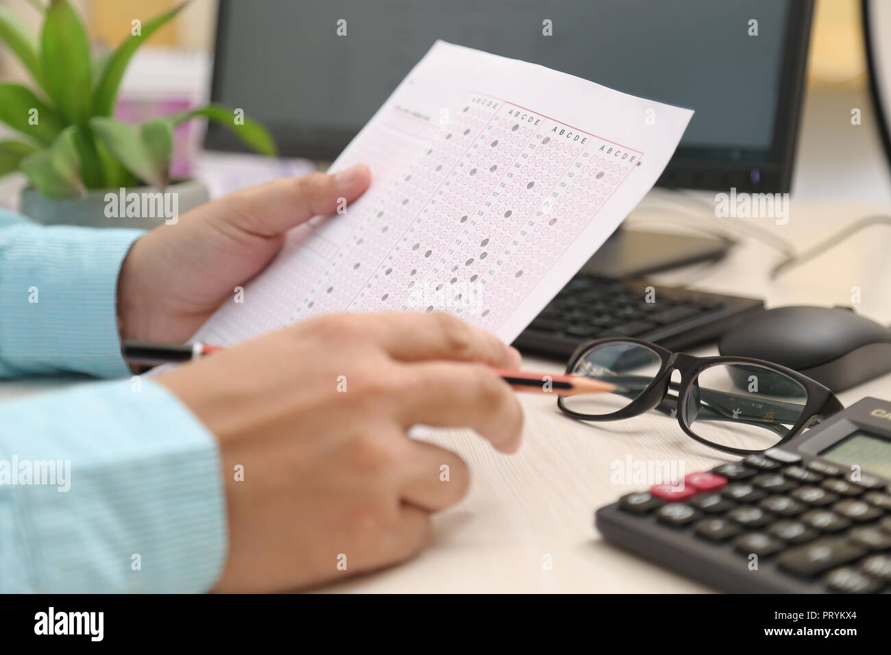 Man holding OMR sheet and pencil in hand. Picture of computer, keyboard ...