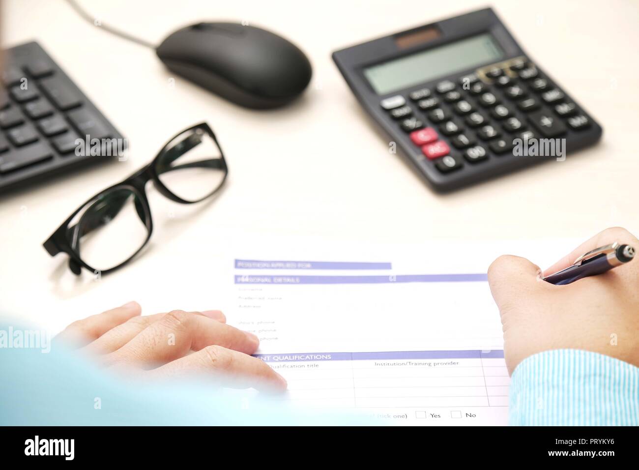 Man is filling form with pen. Picture of calculator, mouse and glasses ...