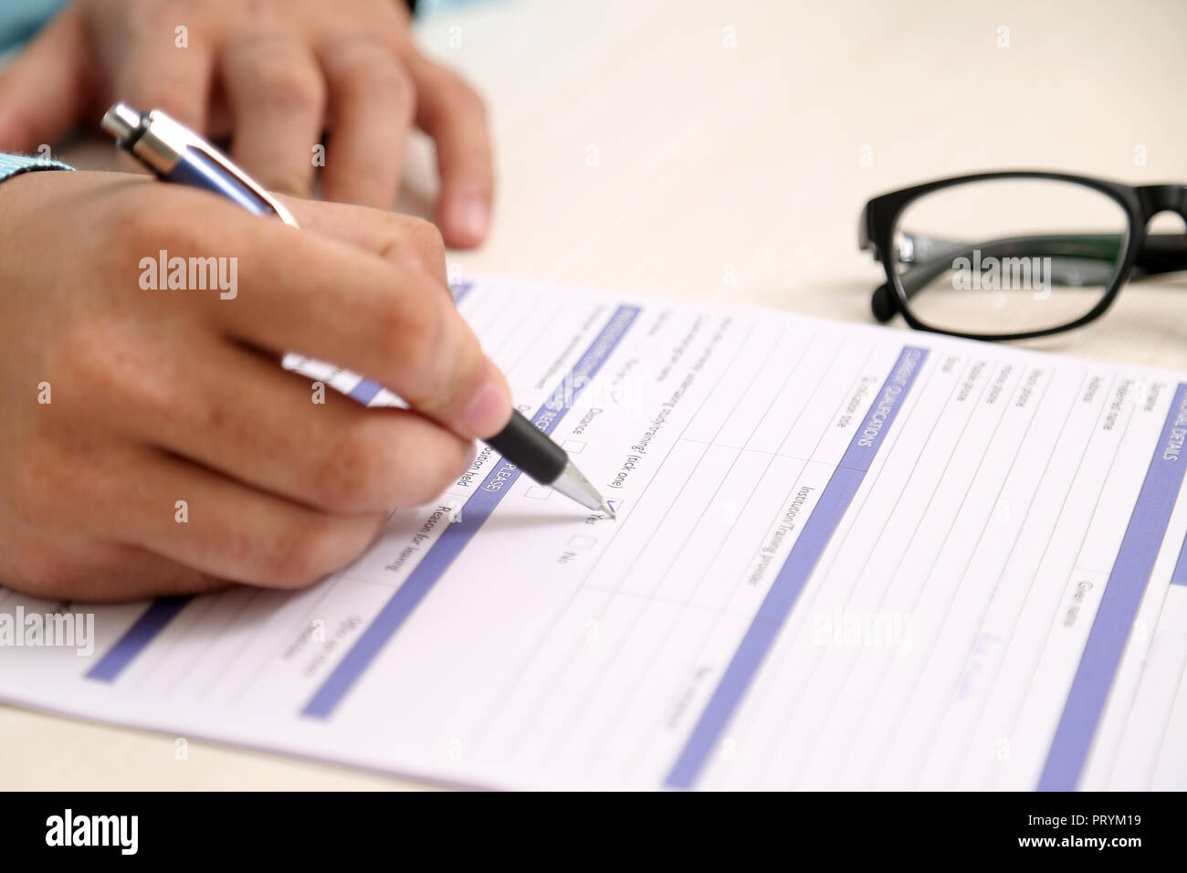 Picture of man hand is filling form with pen. Photo of glasses on the ...