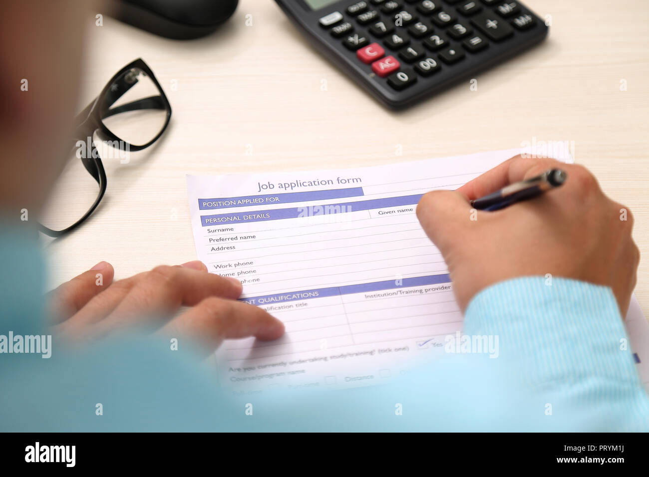 Man is filling form with pen. Picture of calculator and glasses on the ...