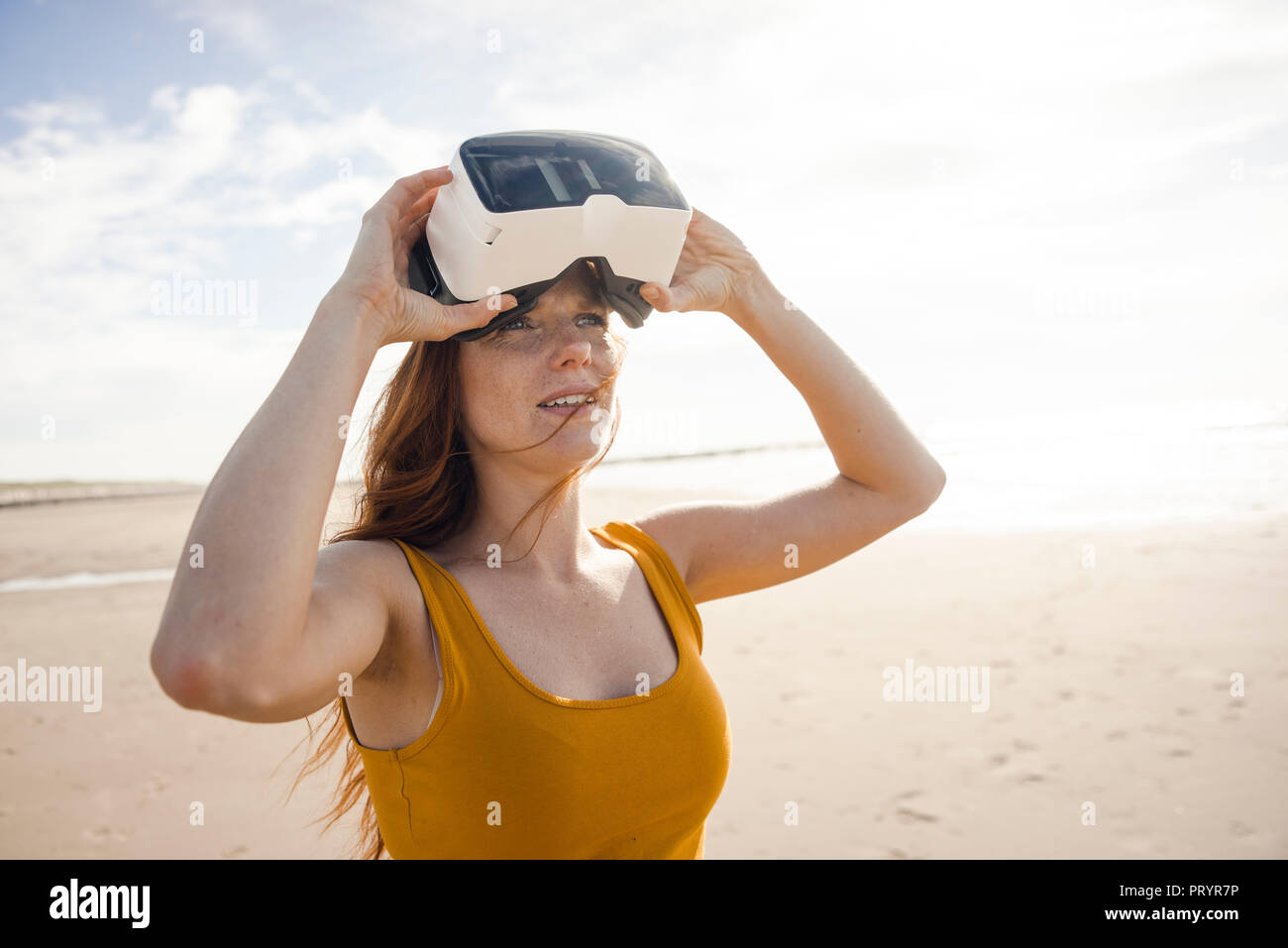 Redheaded woman using VR glasses on the beach Stock Photo - Alamy