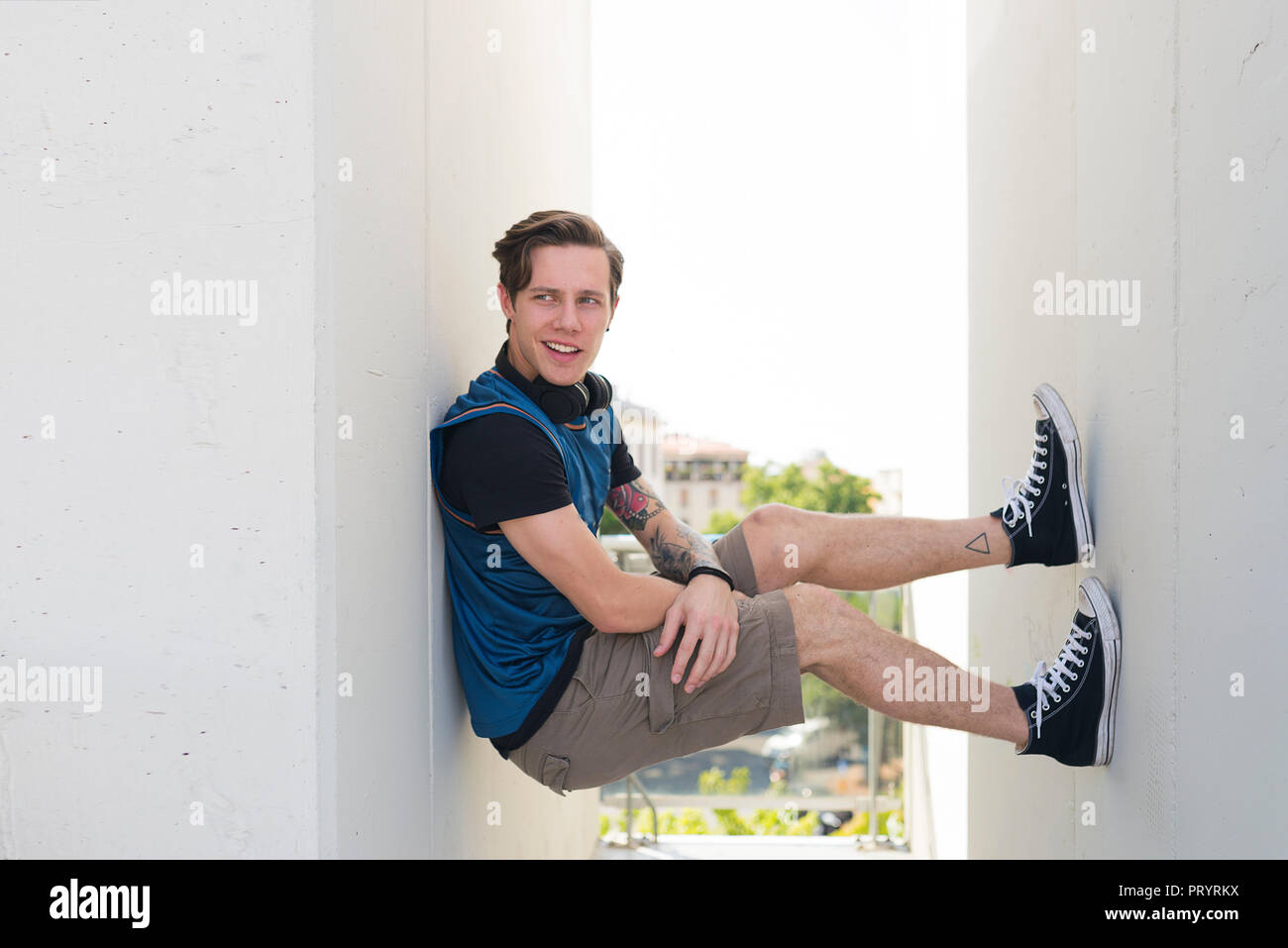 Portrait of tattooed young man in a gap between two facades Stock Photo ...