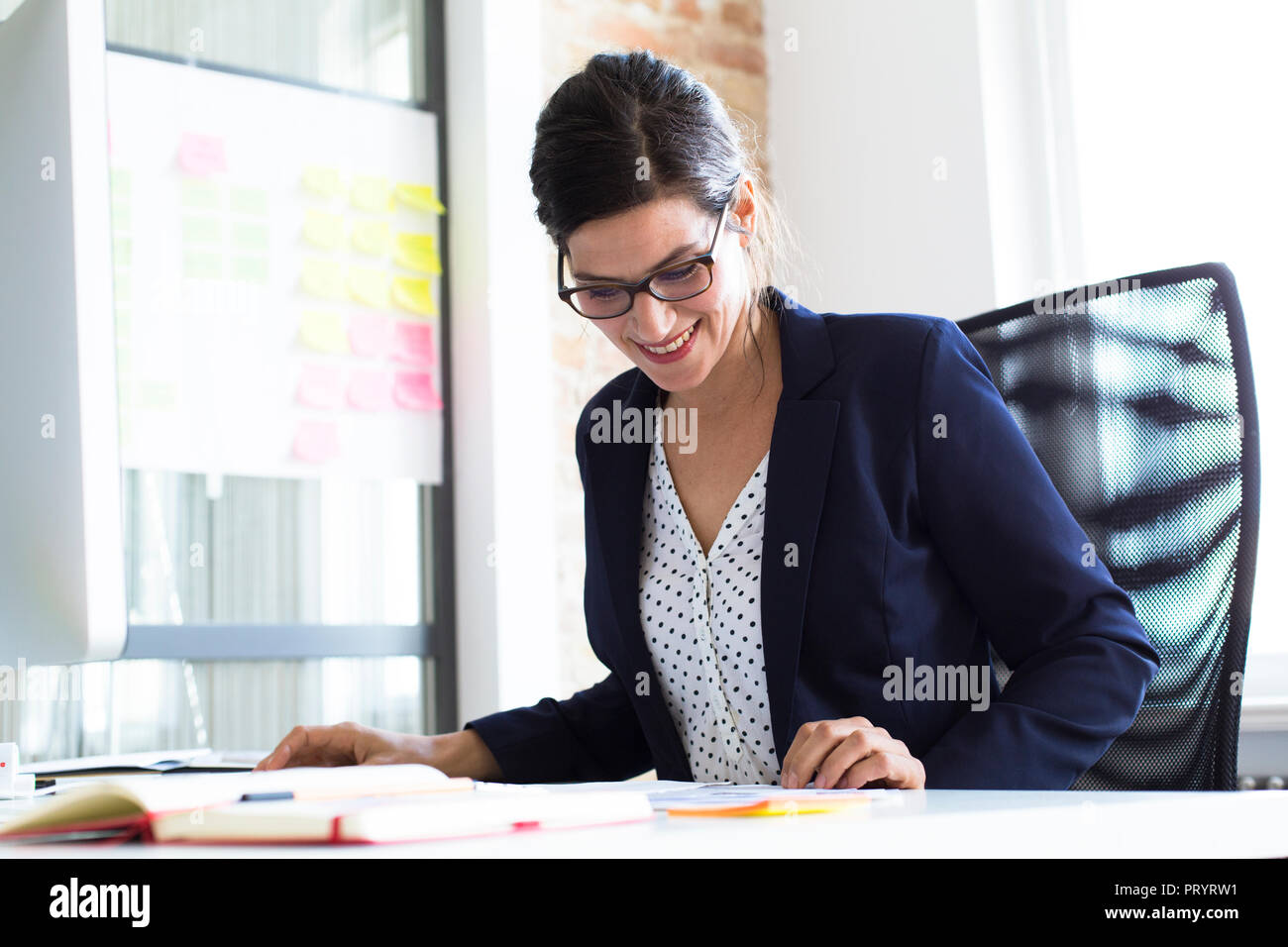 Smiling businesswoman at desk in office Stock Photo - Alamy