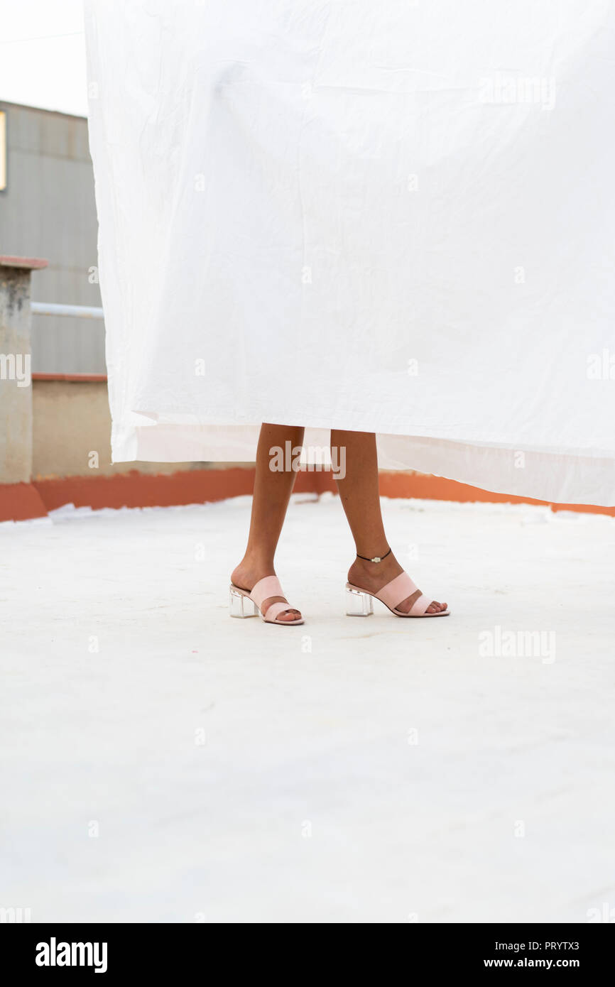 Legs young woman hiding behind drying bed sheet roof terrace hi-res ...