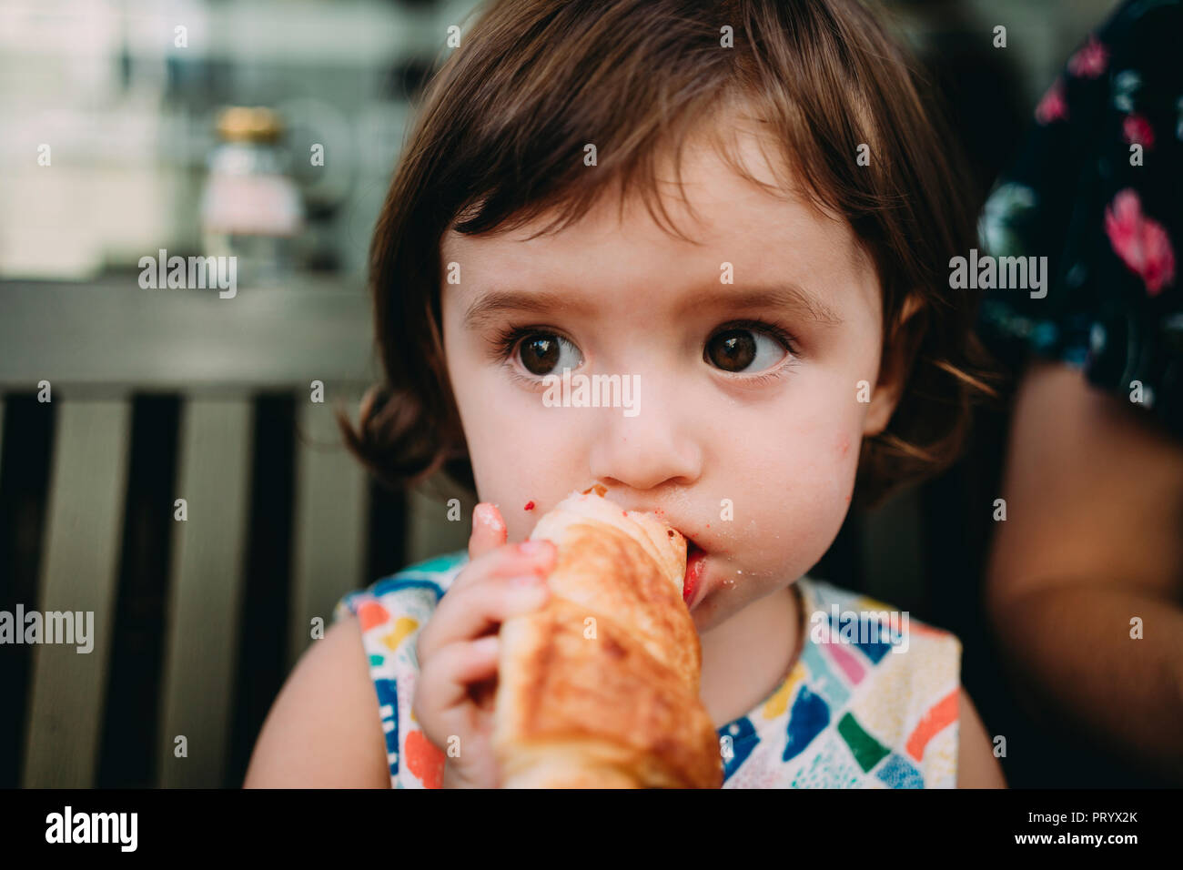 Portrait of baby girl eating a croissant Stock Photo - Alamy