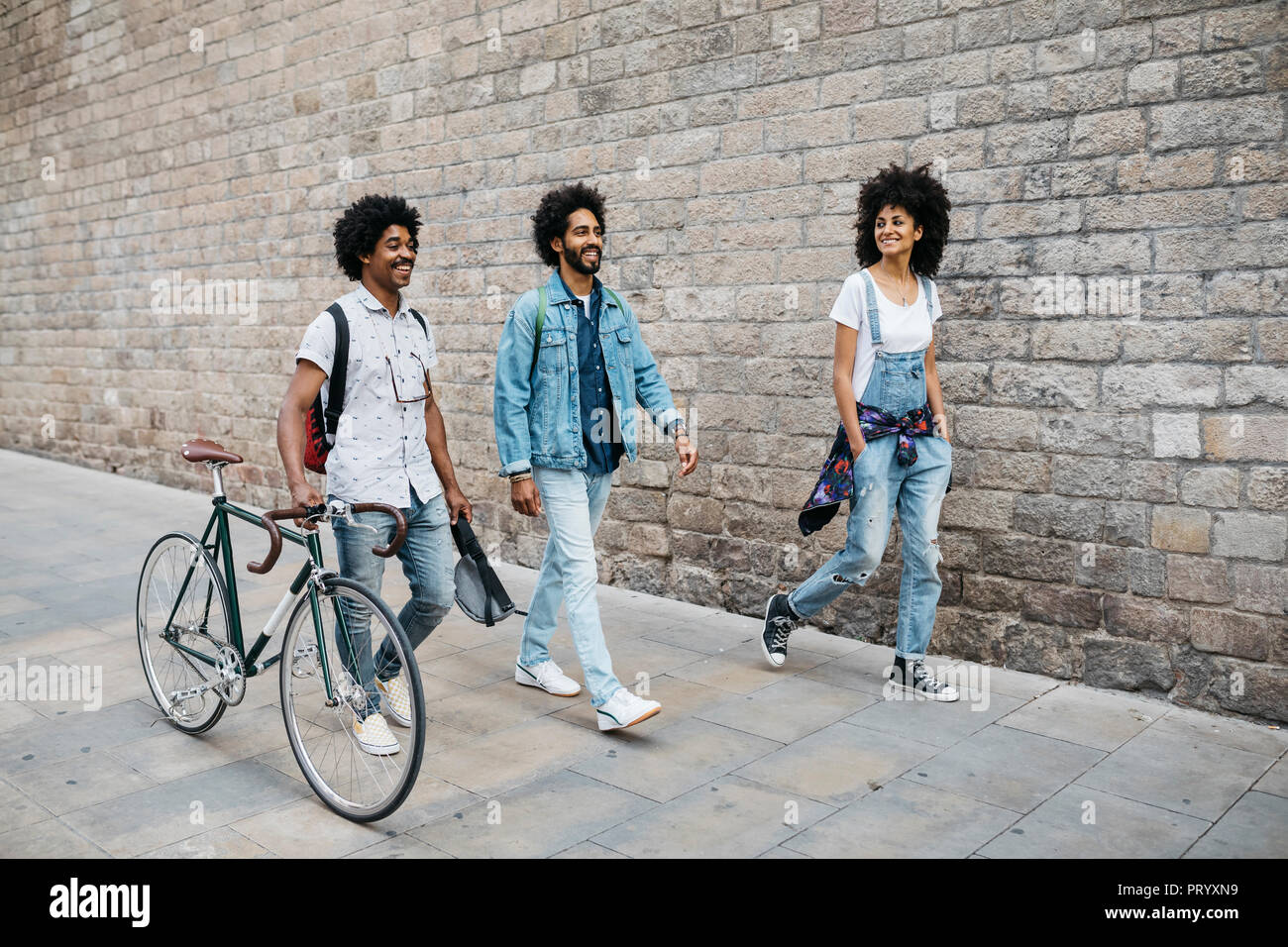Three relaxed friends walking together in the city Stock Photo - Alamy
