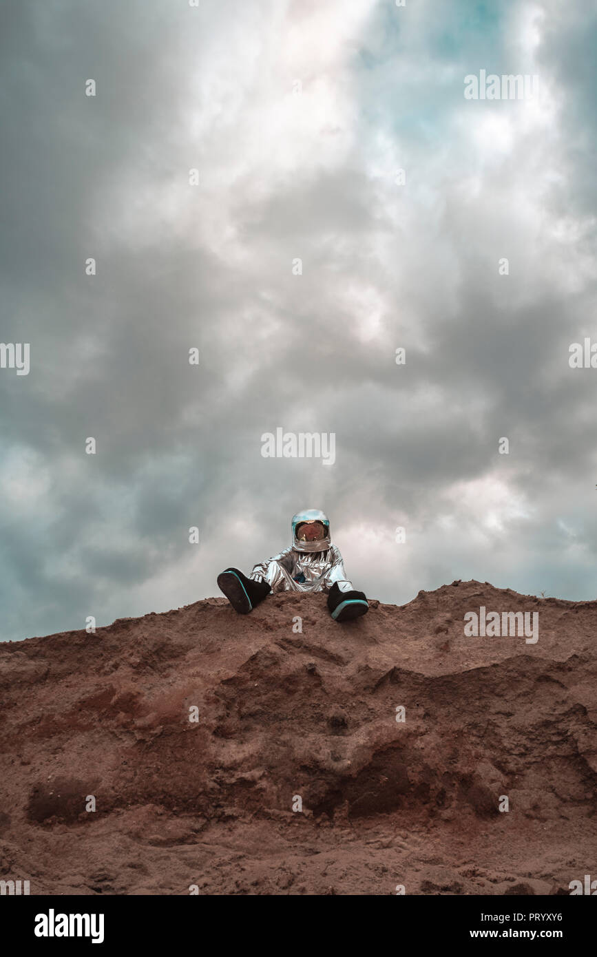Spaceman stitting on slope of nameless planet Stock Photo - Alamy