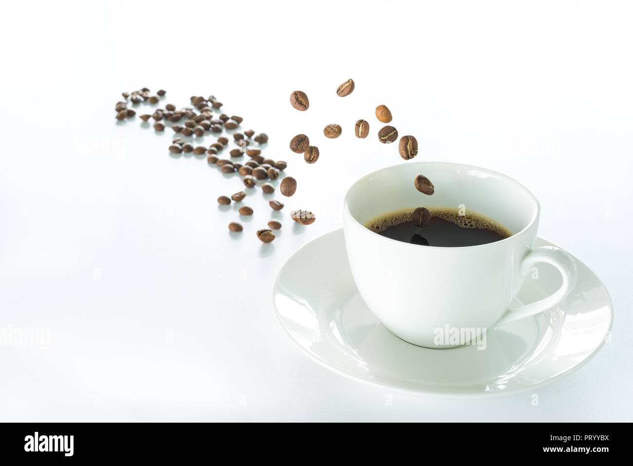 Coffee beans jumping into a white coffee cup Stock Photo - Alamy