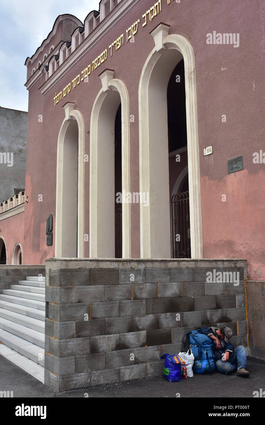 Homeless man with his bags sleeping next to stairway to Jewish ...