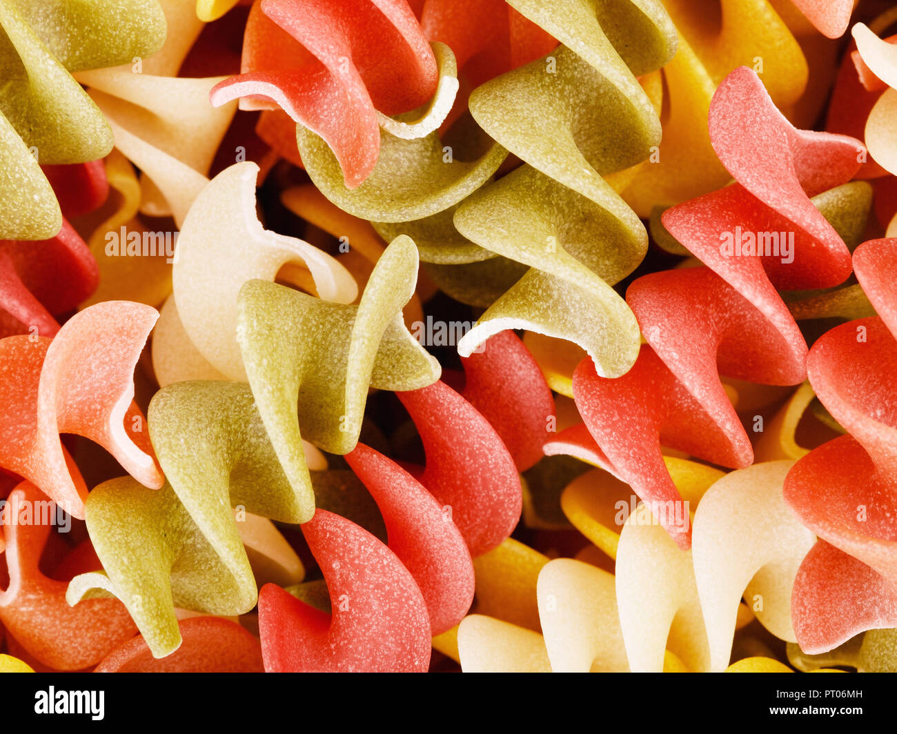raw spiral pasta of different color, background Stock Photo - Alamy