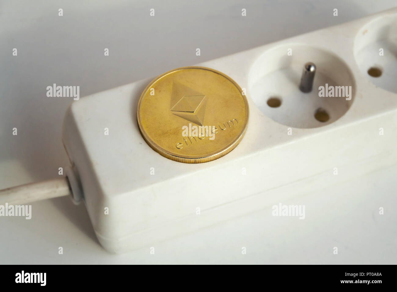 Ethereum coin lying on power strip extension cord with empty socket ...