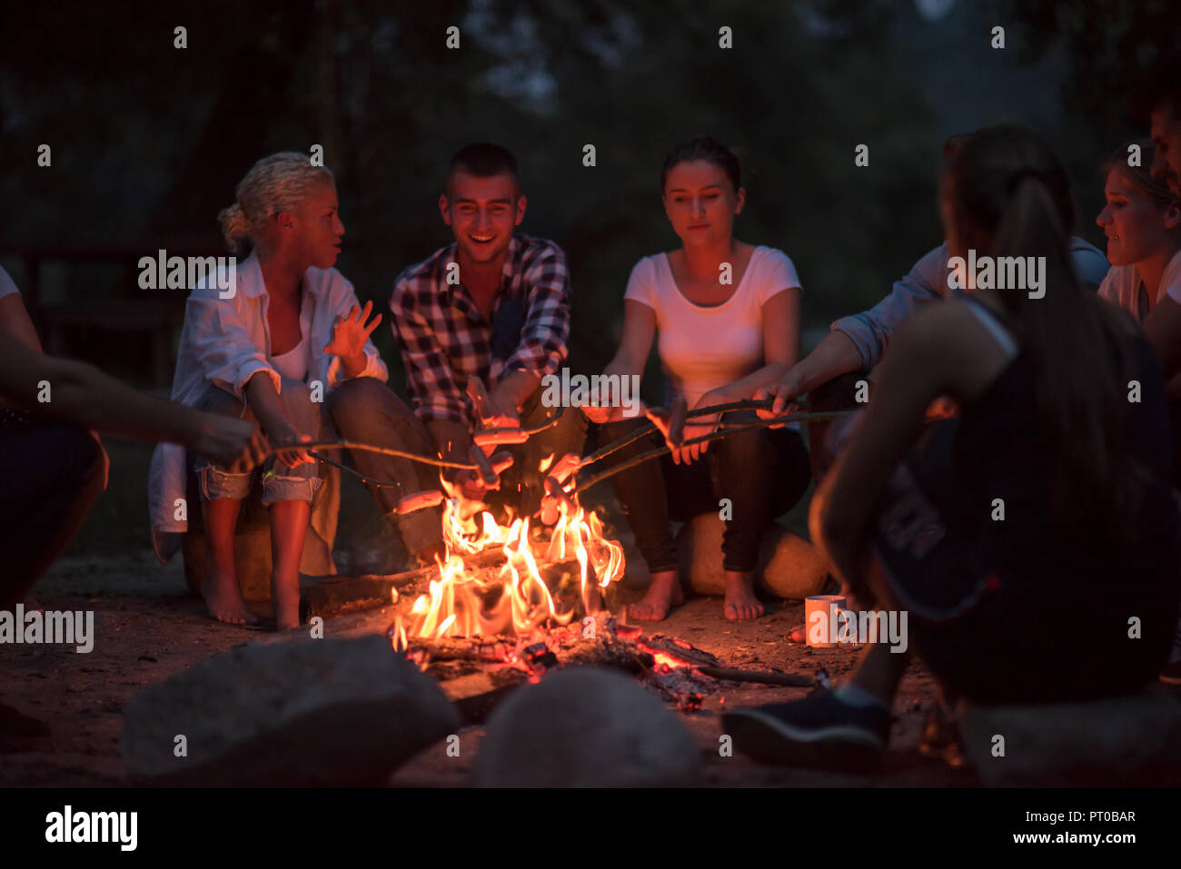 a group of happy young friends relaxing and enjoying summer evening ...