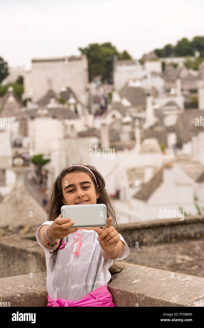 Little girl takes a selfie in front of the trulli of Alberobello Stock ...