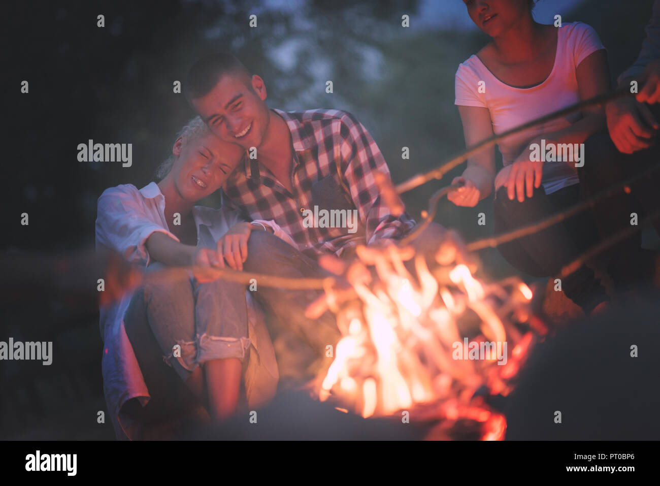 a group of happy young friends relaxing and enjoying summer evening ...