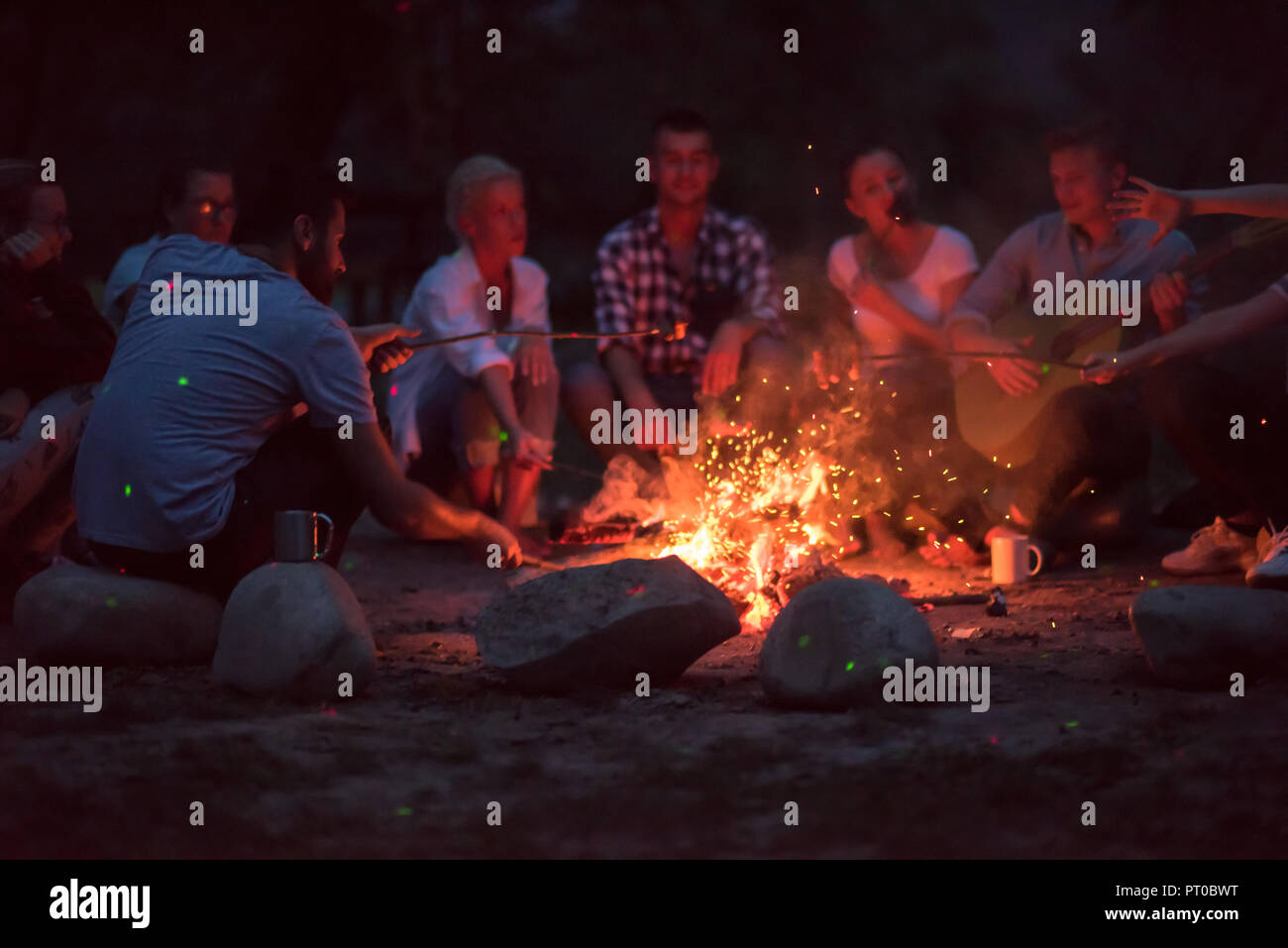 a group of happy young friends relaxing and enjoying summer evening ...