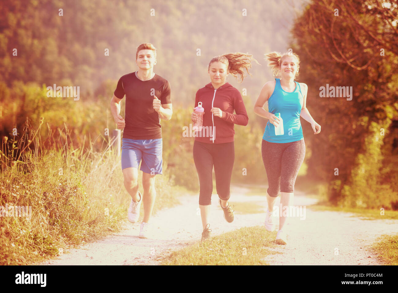 group of young people jogging on country road runners running on open ...