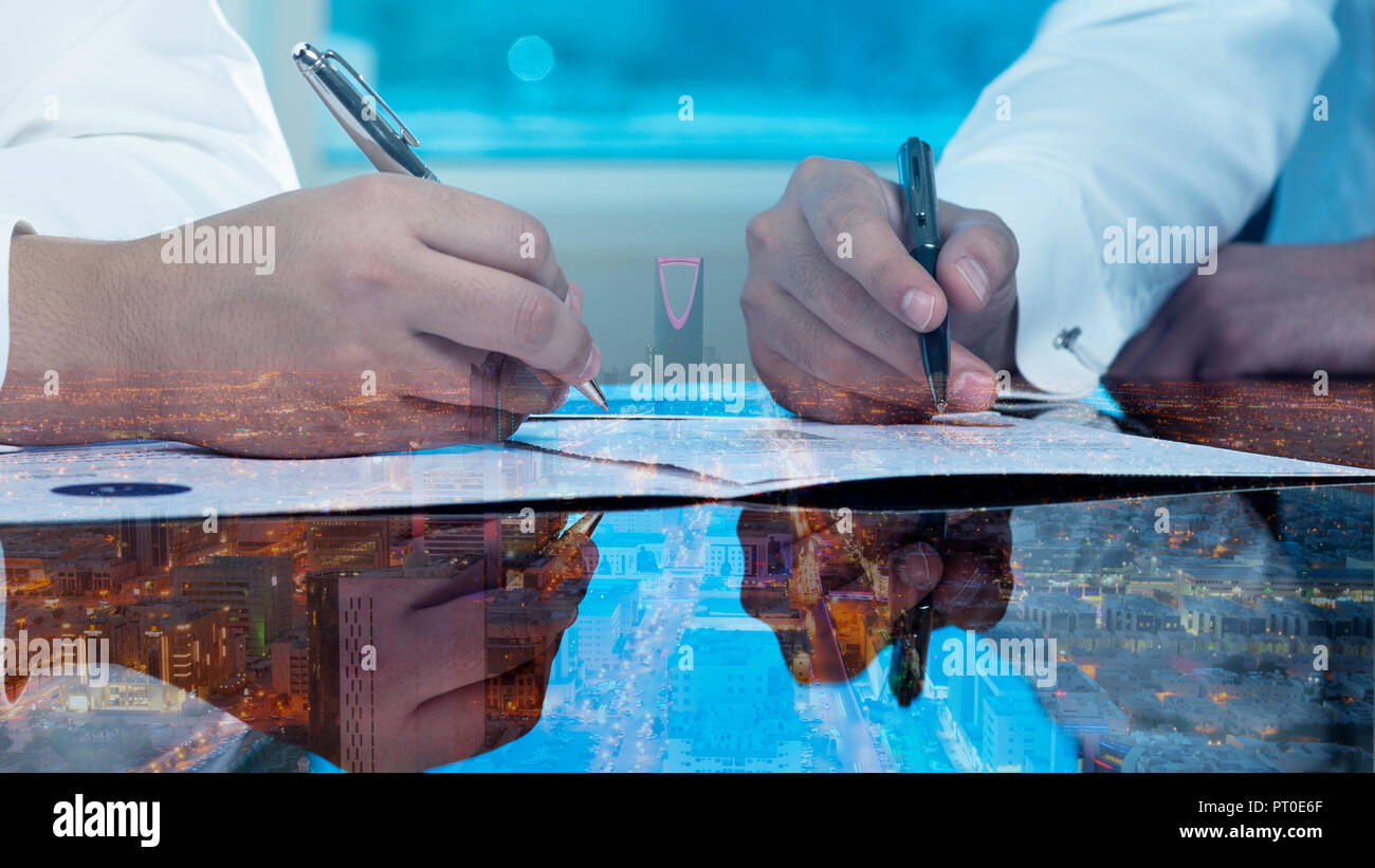 Businessmen hands signing documents on Riyadh skyline city scape ...
