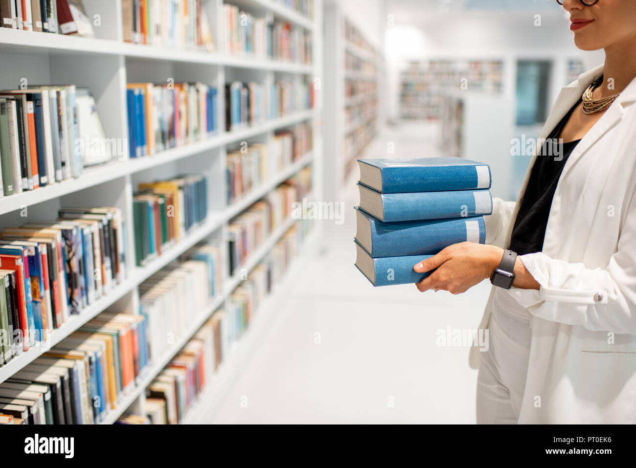 Holding books with bookshelves on the background at the modern library ...