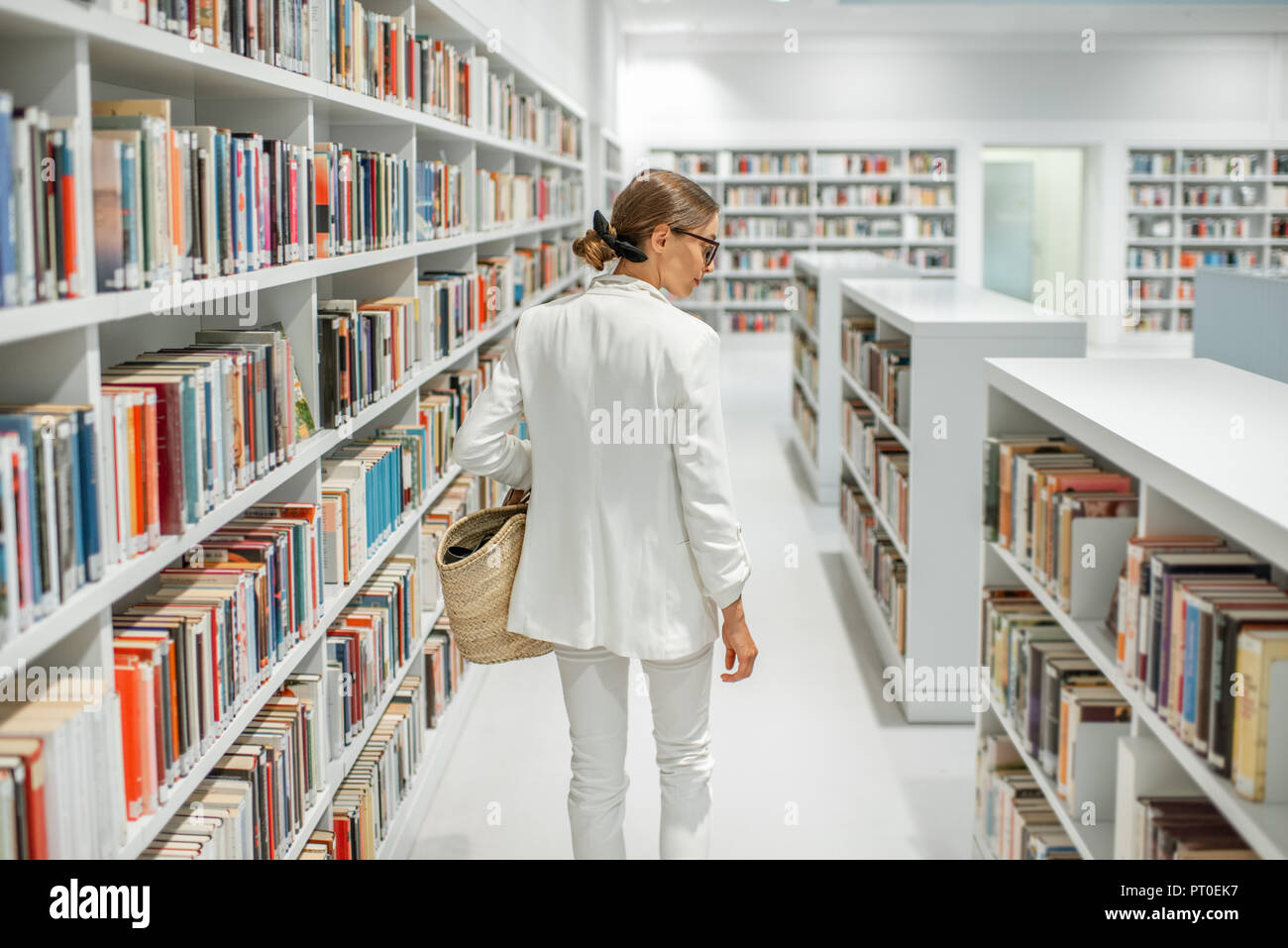 Young woman searching books walking at the modern library interior with ...