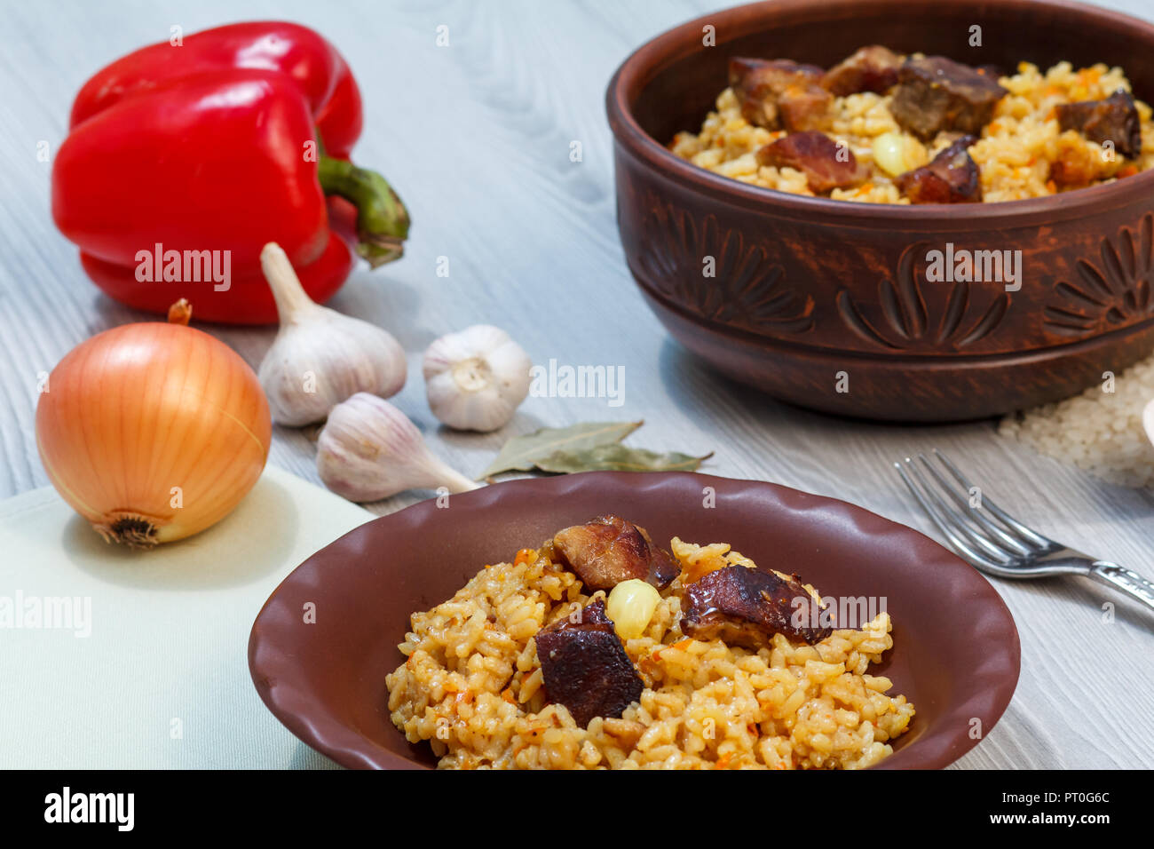 Rice pilaf on clay plate and bowl with meat and vegetables - onion ...