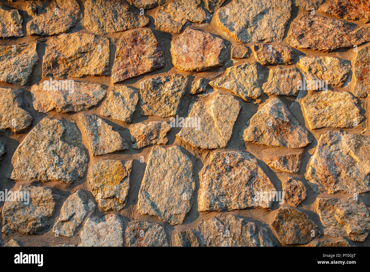 Fragment of sunlit stone wall at sunset. Front view Stock Photo - Alamy