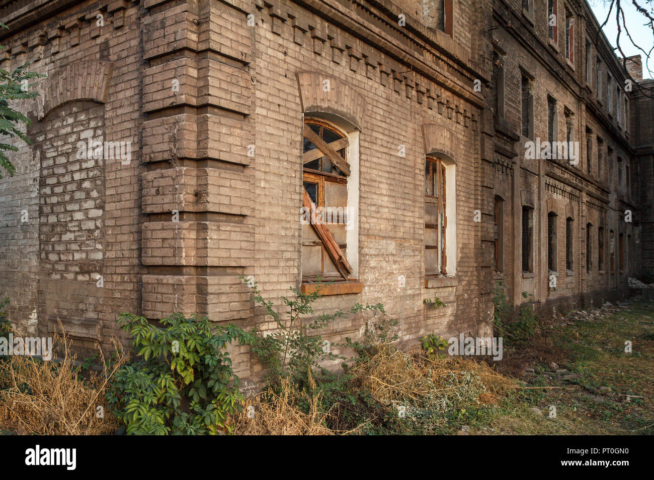 Facade of old abandoned brick building with window lined with wooden ...
