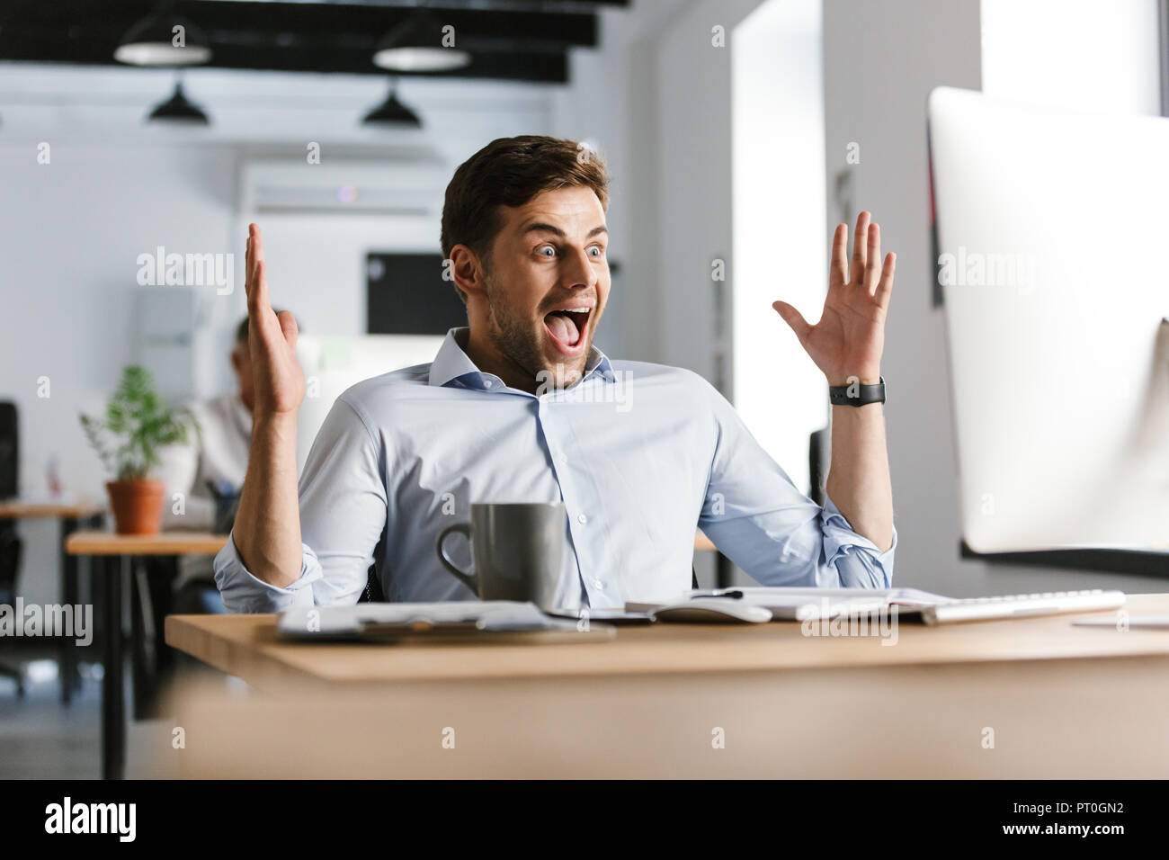 Surprised happy male manager rejoices while using computer and sitting ...