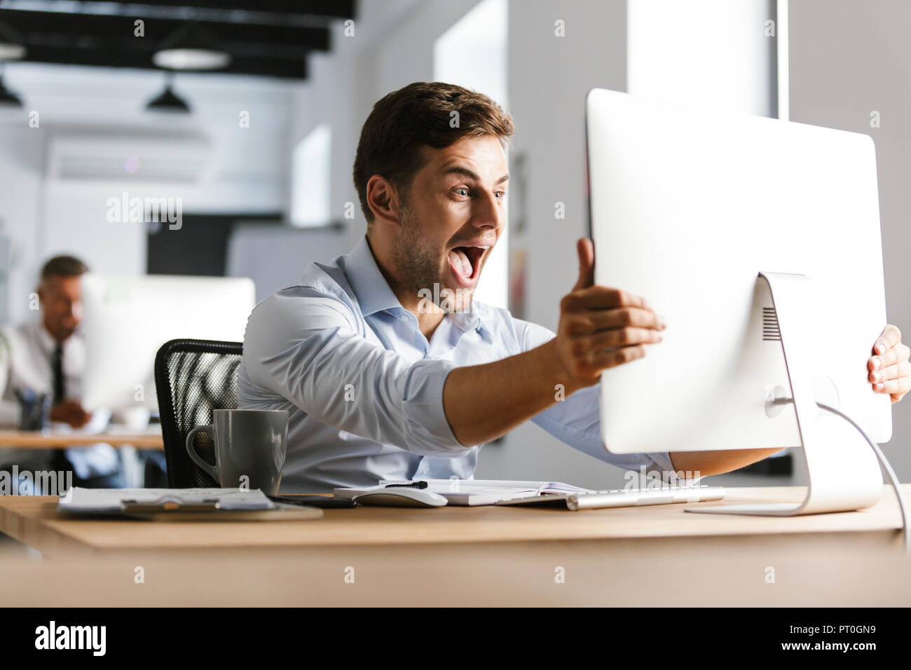 Surprised happy male manager screaming and rejoices while holding ...