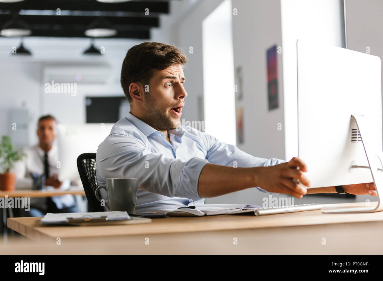 Picture of Shocked male manager using computer while sitting by the ...