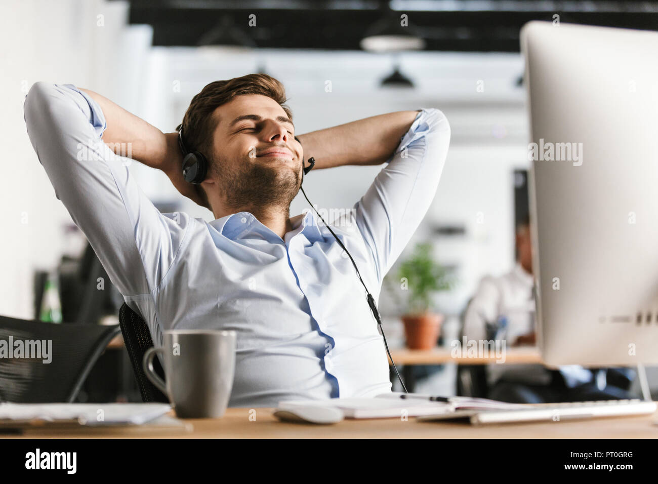 Cheerful office manager talking by headset with microphone while ...