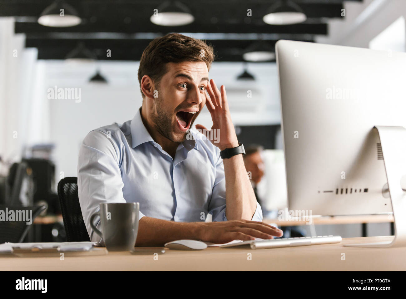 Surprised screaming business man using computer while sitting by the ...
