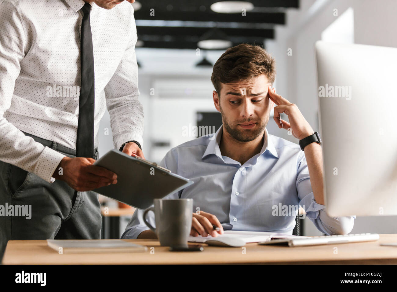 Image of handsome tired bored displeased man sitting in office working ...