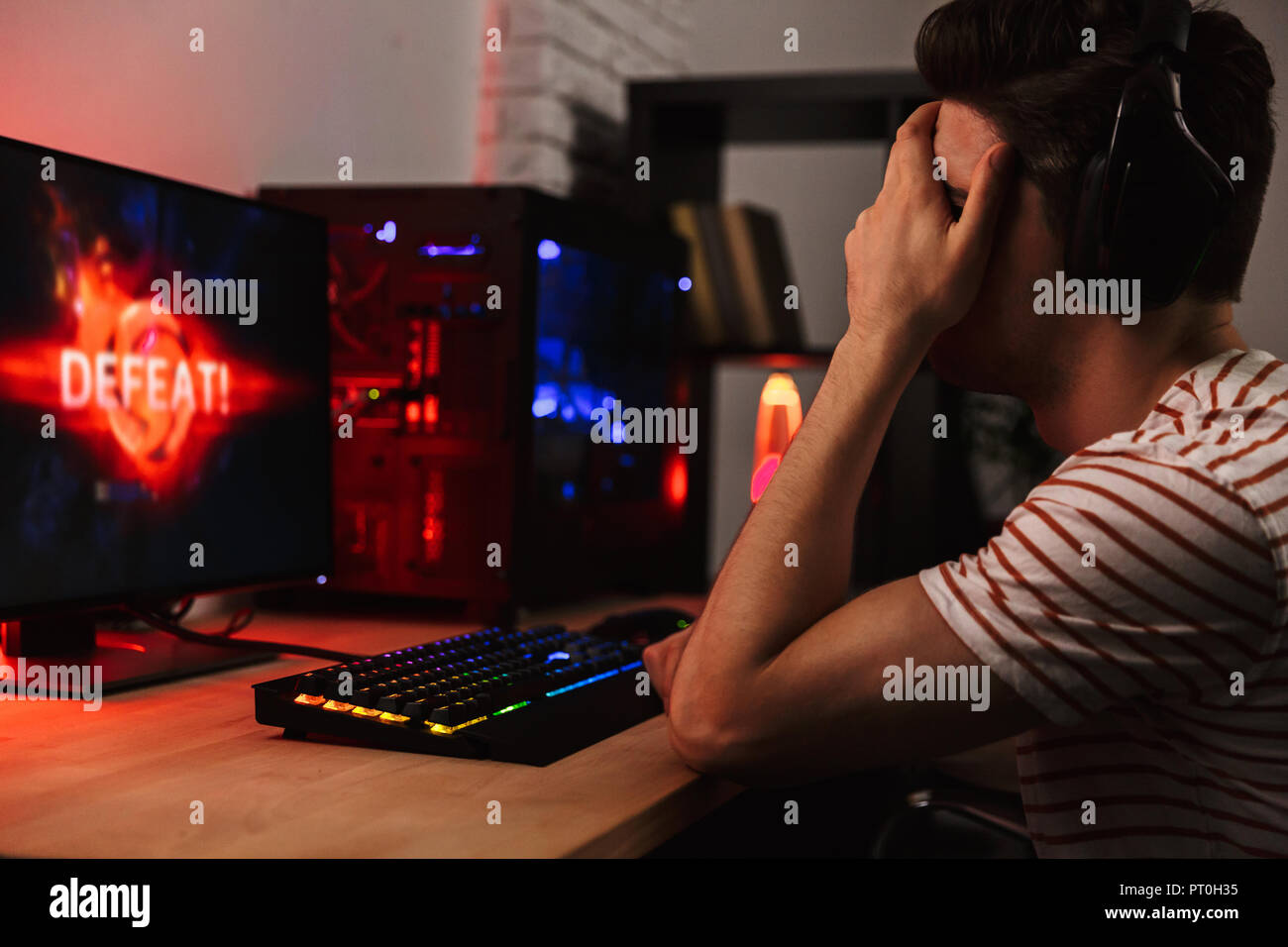 Side view of Upset gamer playing video games on computer and covering ...