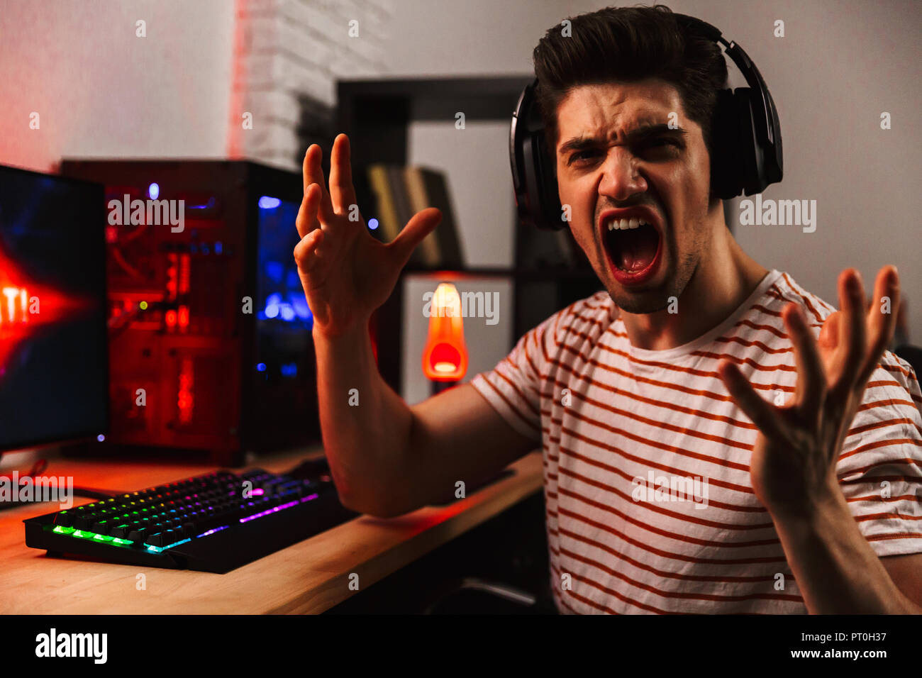 Side view of Screaming gamer playing video games on computer while ...