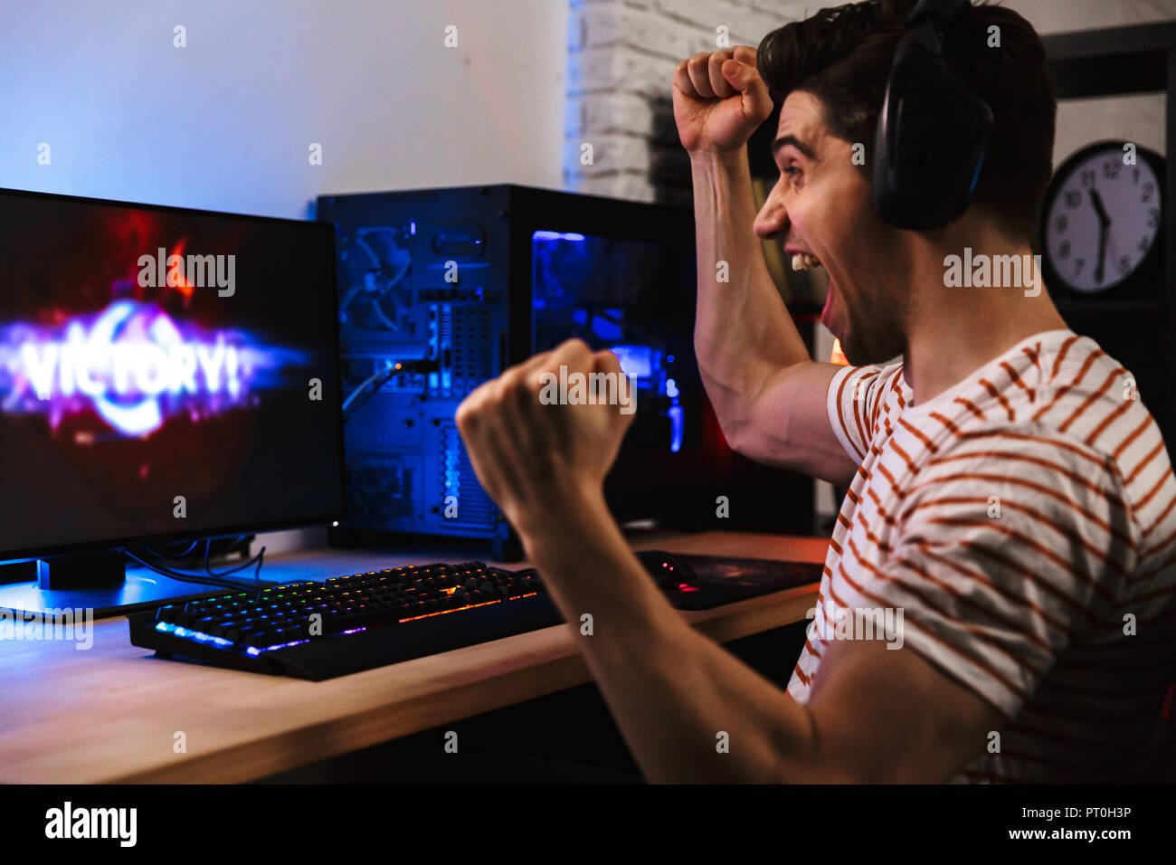Side view of Cheerful gamer playing video games on computer and ...