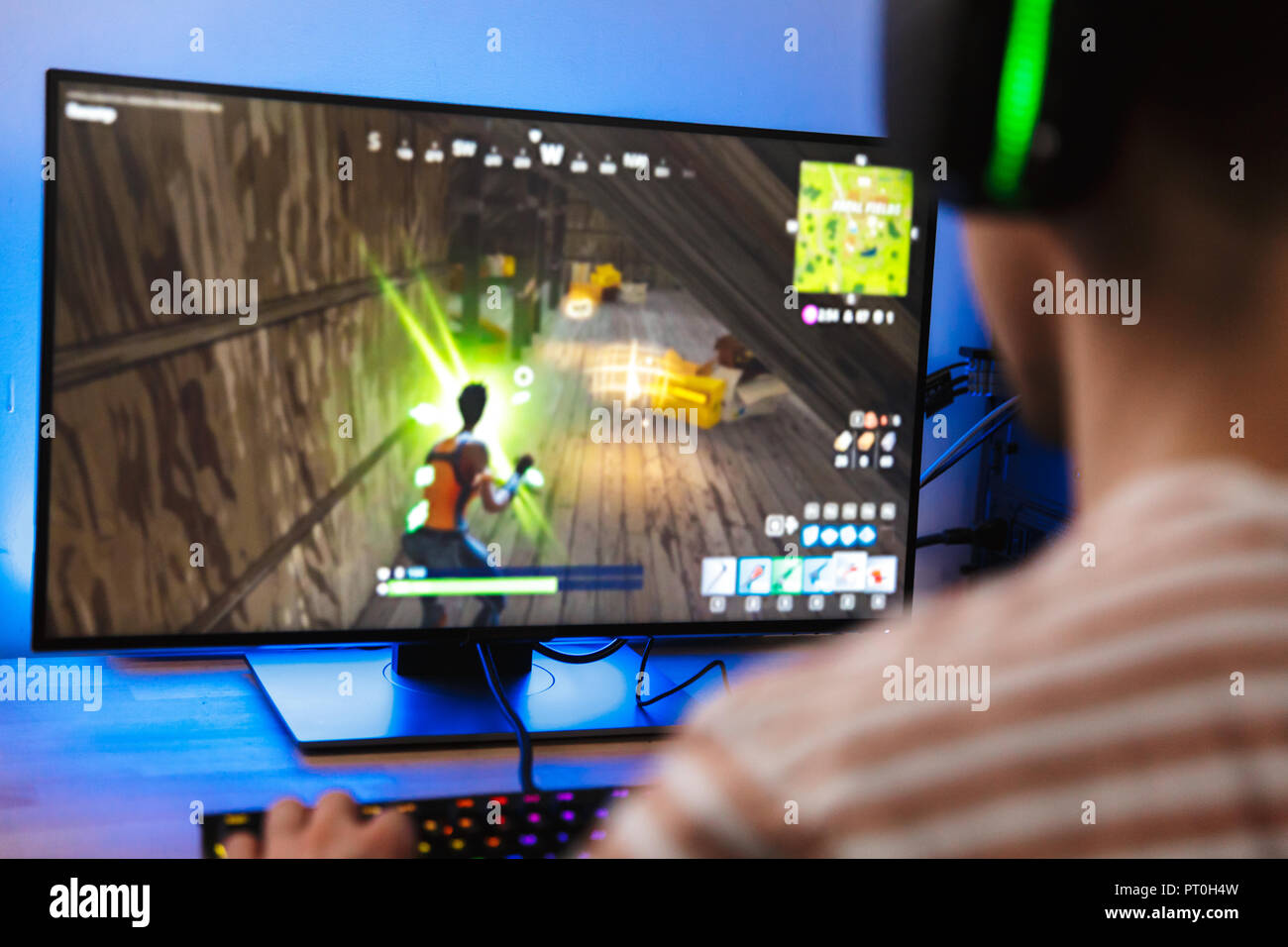 Back view of gamer playing video games on computer while sitting by the ...