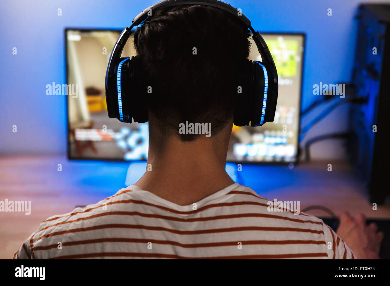 Back view of young gamer playing video games on computer while sitting ...