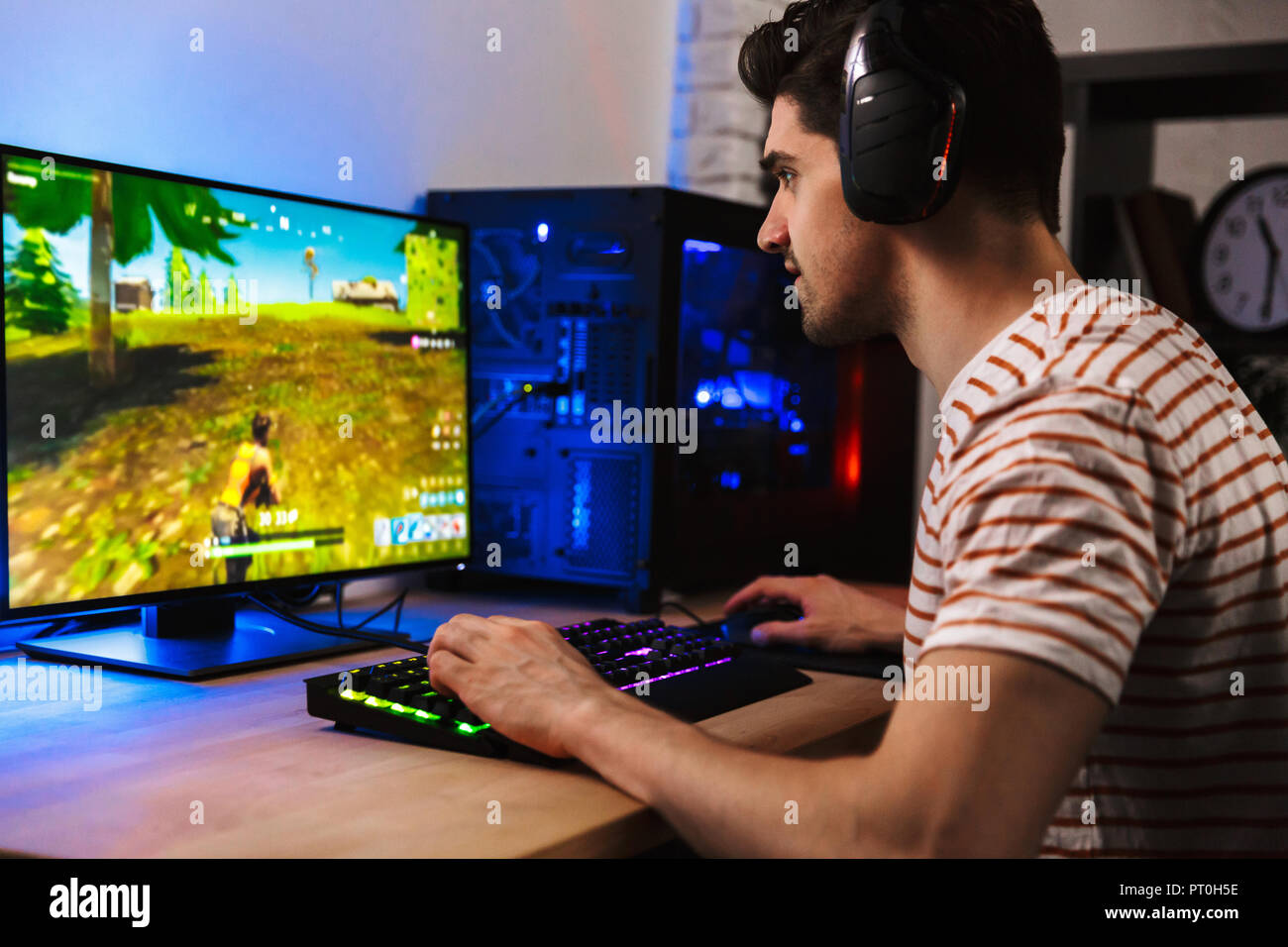 Image of young man playing video games on computer wearing headphones ...