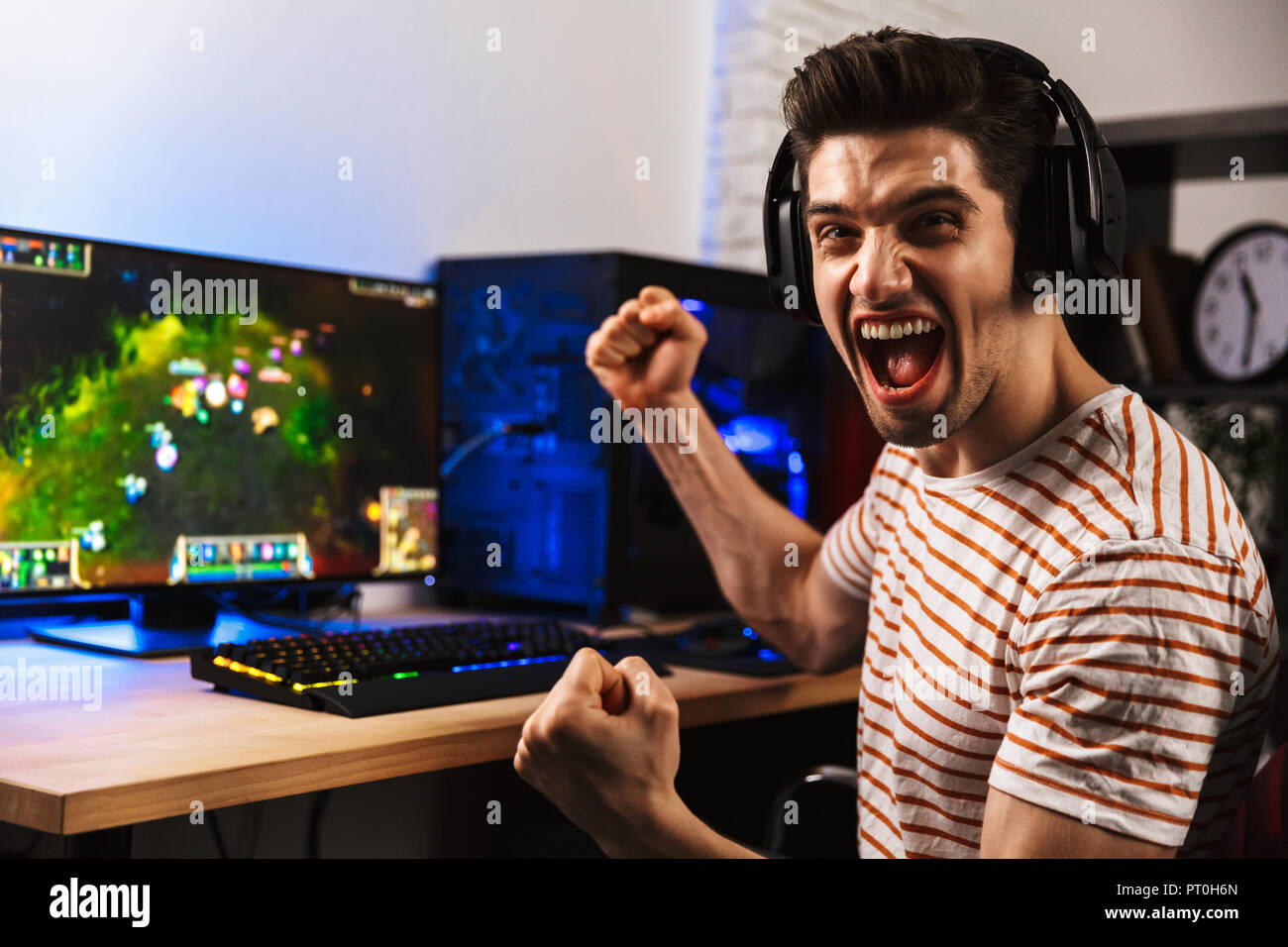 Portrait of happy man playing video games on computer wearing ...