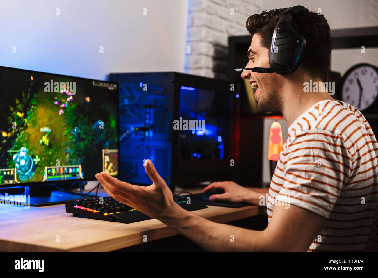 Image of cheerful gamer man playing video games on computer wearing ...